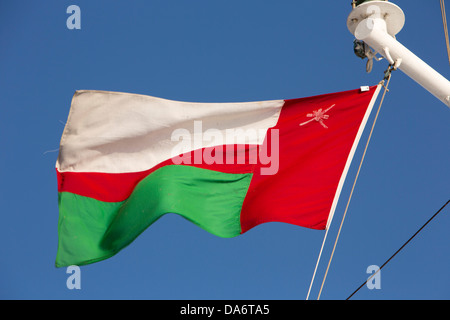 National flag of Oman flying from pole on top of old fort close to ...
