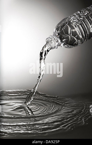A white liquid stream falling into a puddle of water in the middle of a ...