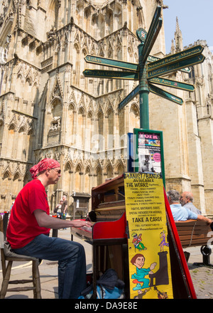 Street musician or busker playing a piano mounted on a bicycle and ...