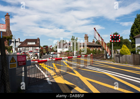 Barriers fall at an English level crossing as a train approaches in the ...
