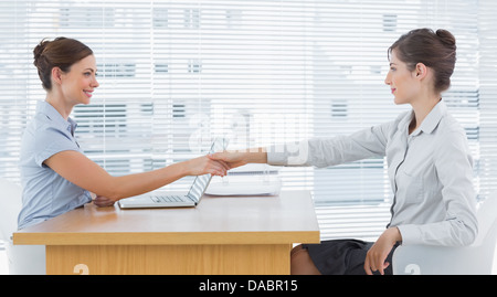 Businesswoman shaking hands with interviewee at desk in office Stock ...