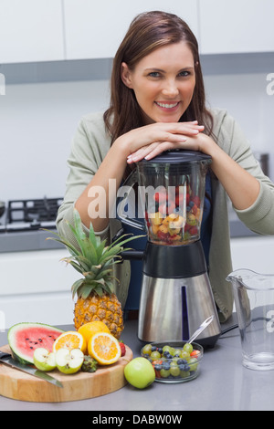 Portrait of young smiling woman with a blender full of vegetables in ...