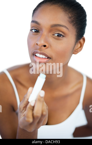 Portrait, skincare and lip balm with a black woman in studio on a blue ...