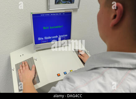 A young man demonstrates the usage of a 'Hand-Foot-Clothing-Monitor' at ...