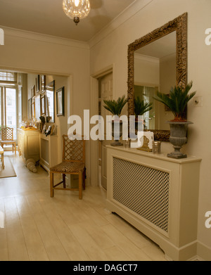 Gilt mirror hanging over radiator cover in neutral open plan hallway ...