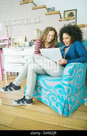 African american woman using laptop and smartphone sitting on table at ...