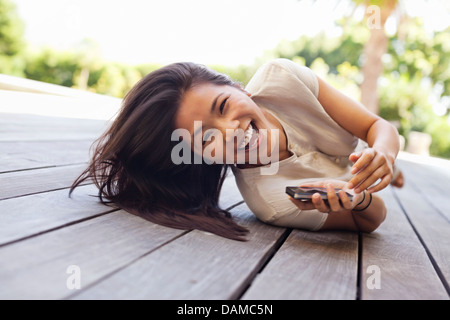 Happy brunette woman playing mobile video game, smiling and looking at ...