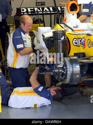 F1 mechanics at work on a Renault F1 race car in the pit lane workshop ...