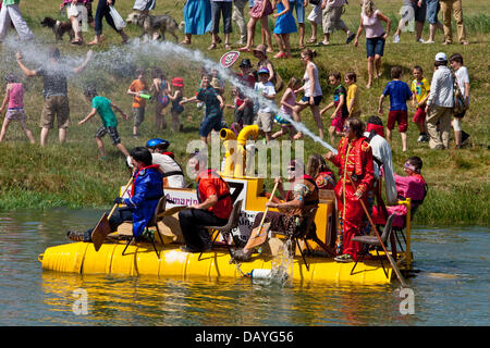 Local children throw eggs and flour bombs at the home made rafts taking ...