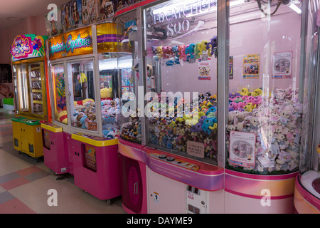 Arcade with claw crane game machines and child playing with coin pusher ...