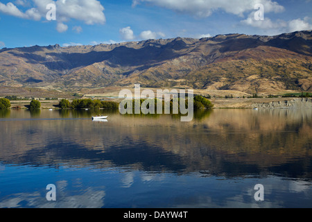 Lake Dunstan, Pisa Range, and people in boat fishing, Central Otago ...