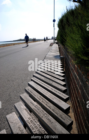 A seafront with wooden benches on one side and a white wooden canopy on ...