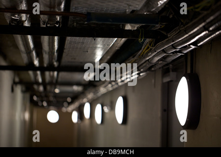 An underground basement passage way, dimly lit with pipes and services ...