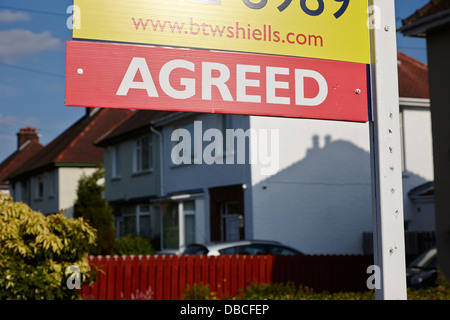Sale agreed sign / board in vibrant orange and purple, against a green ...