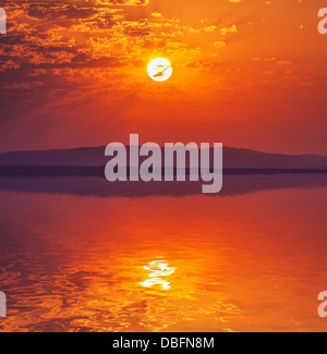 Vibrant rising sun at dawn over water Stock Photo - Alamy