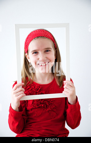 Girl looking through picture frame, having photograph taken Stock Photo ...