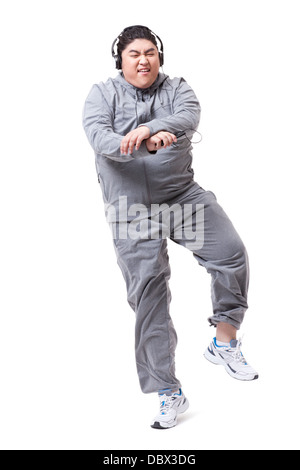 Smiling overweight man listening music on headphones while standing by ...