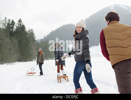 Happy friends pulling sleds in snowy field Stock Photo - Alamy