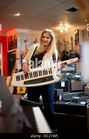 Female musician playing a keytar and standing isolated on white ...
