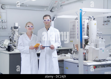 People in lab coats standing and using tablet Stock Photo - Alamy