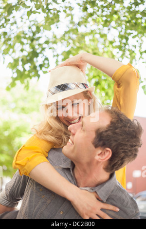 Smiling woman riding piggyback on man shoulders. Happy young couple ...