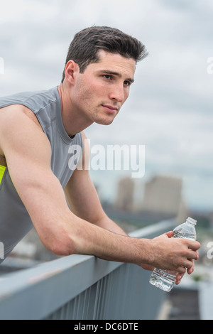 Young man leaning against railing on balcony Stock Photo - Alamy