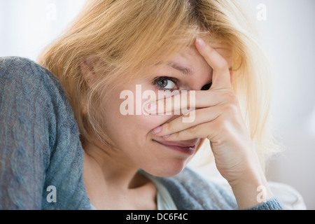 Embarrassed young woman covering face with hand on white background ...