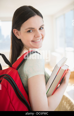 Portrait of happy student woman holding books with thumb up against ...
