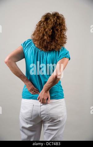 A 50 year old red haired woman demonstrates lower back pain Stock Photo ...