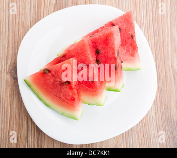 Slices of ripe watermelon on plate with a knife on white wooden ...