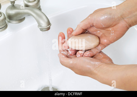 Horizontal photo of female hands lathering in liquid soap with bathroom ...