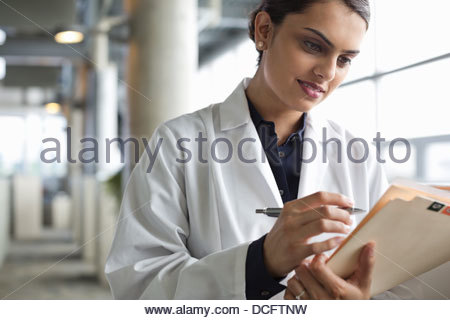 Female doctor taking notes on clipboard in medical office; panoramic ...