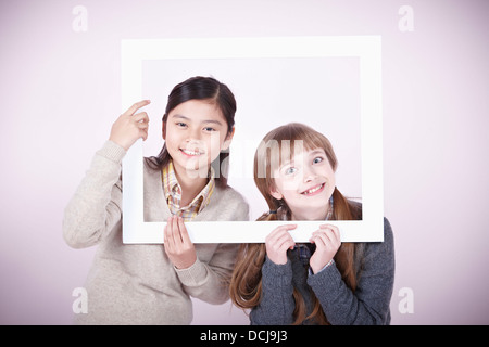 two girls with empty frame around themselves Stock Photo - Alamy
