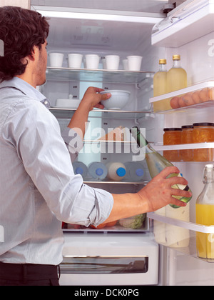 Adult man standing at refrigerator, choosing frozen convenience food in ...