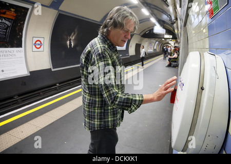 Passenger using a London underground help point Stock Photo - Alamy