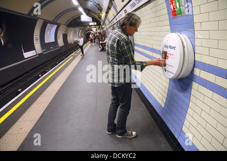 Passenger using a London underground help point Stock Photo - Alamy