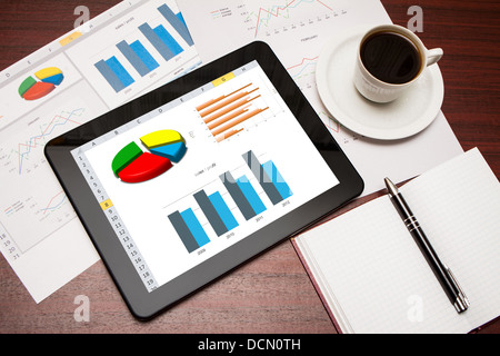 Modern tablet computer with business charts on screen against grey ...