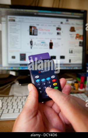 fingers keying Online Banking security card-reader in front of computer ...