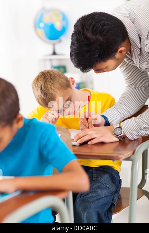 caring primary educator helping a student in classroom Stock Photo - Alamy
