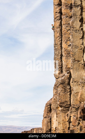 A woman climbing a basalt rock cliff in central Washington State, USA ...