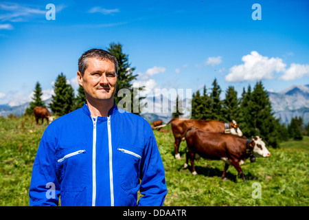 Herdsman standing in front of cows in alpine mountains Stock Photo - Alamy