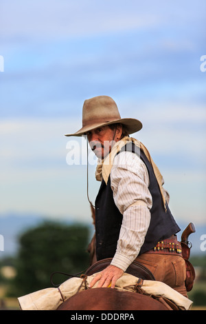 A cowboy looking back while riding his horse Stock Photo - Alamy