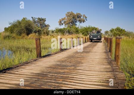 A wooden bridge in the Okavango delta leads across water to the Stock ...