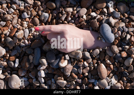 Girls hand buried in pebbles Stock Photo - Alamy