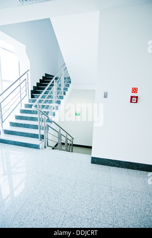 Modern office stairs in corridor with emergency exit illuminated sign ...