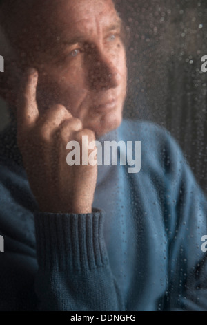 Serious mature man behind rainy window pane Stock Photo - Alamy