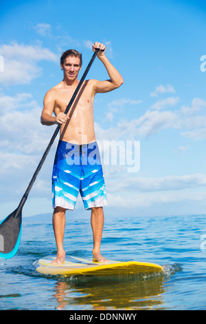A man on a stand-up paddle board catching waves with the horizon of the ...
