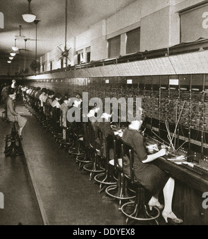 1930s WOMAN TELEPHONE OPERATOR AT SWITCHBOARD LOOKING AT CAMERA SMILING ...
