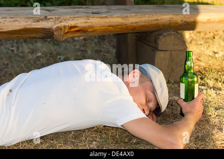 Alcoholic passed out on the ground in a park lying with his head ...