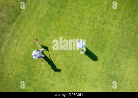Aerial view of players on a green golf course. Golfer playing on ...